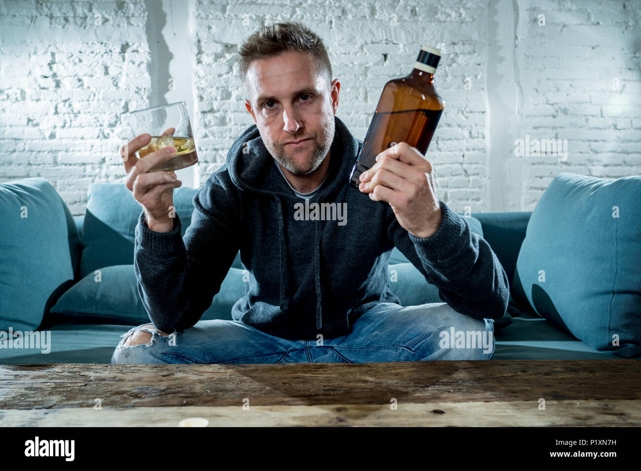 drunk alcoholic unemployed man drinking whiskey from the glass and bottle depressed wasted and ...