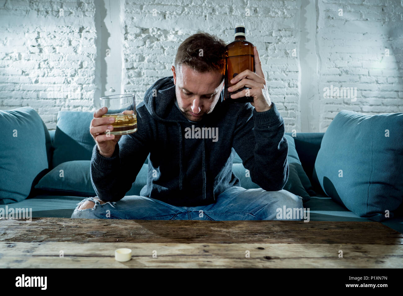 drunk alcoholic unemployed man drinking whiskey from the glass and bottle depressed wasted and ...
