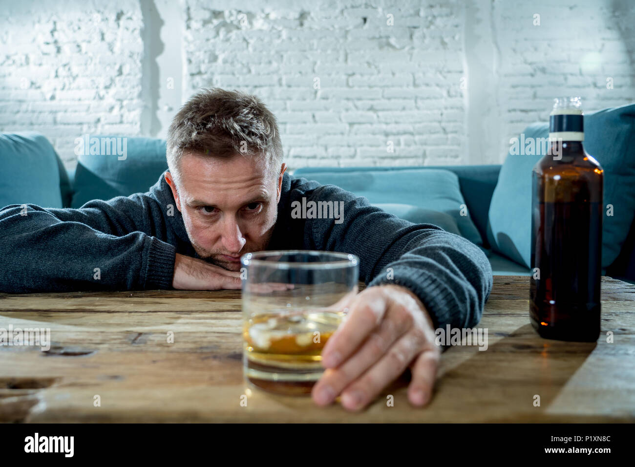 drunk alcoholic unemployed man drinking whiskey from the glass and bottle depressed wasted and ...