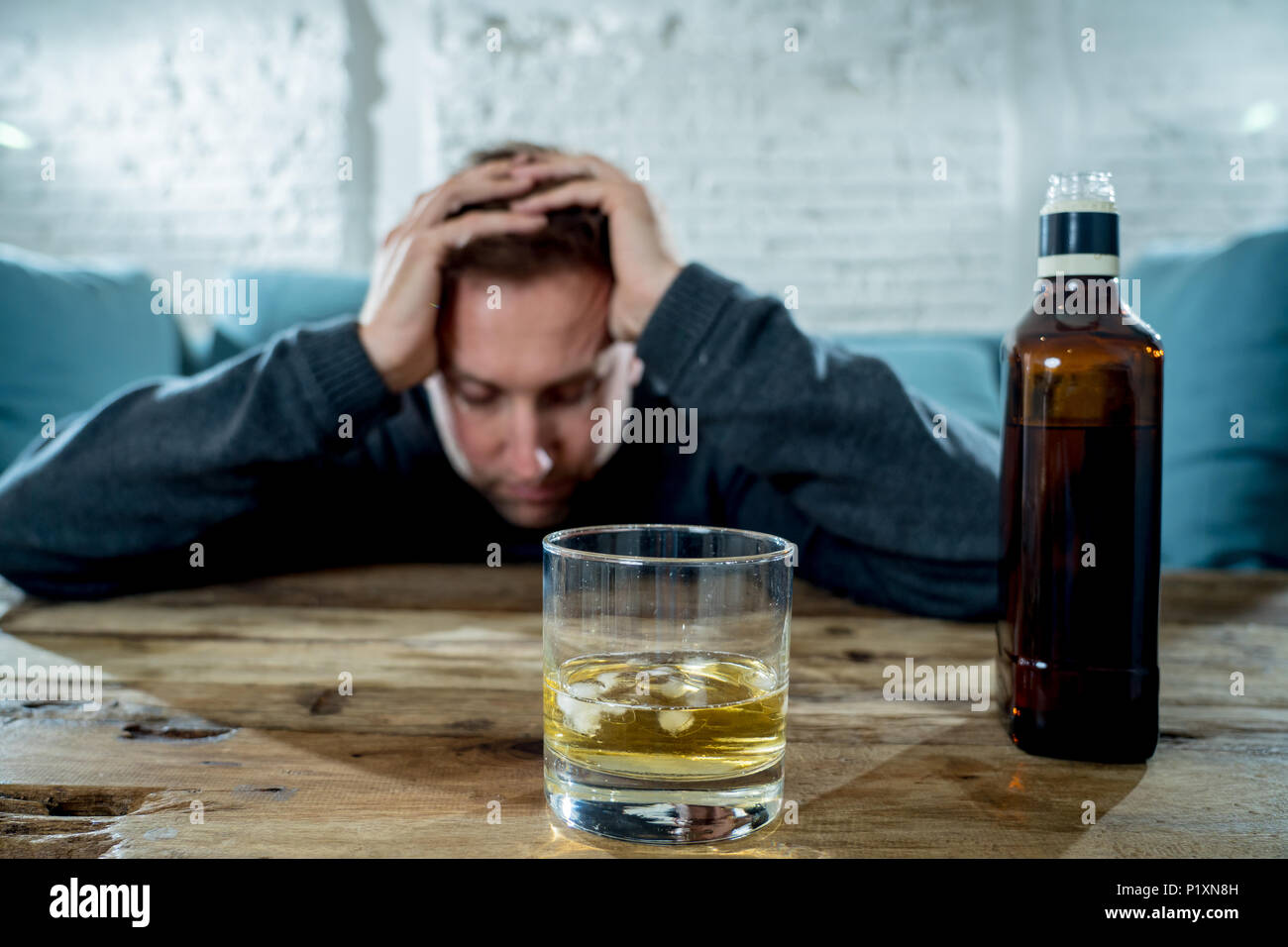 drunk alcoholic unemployed man drinking whiskey from the glass and bottle depressed wasted and ...