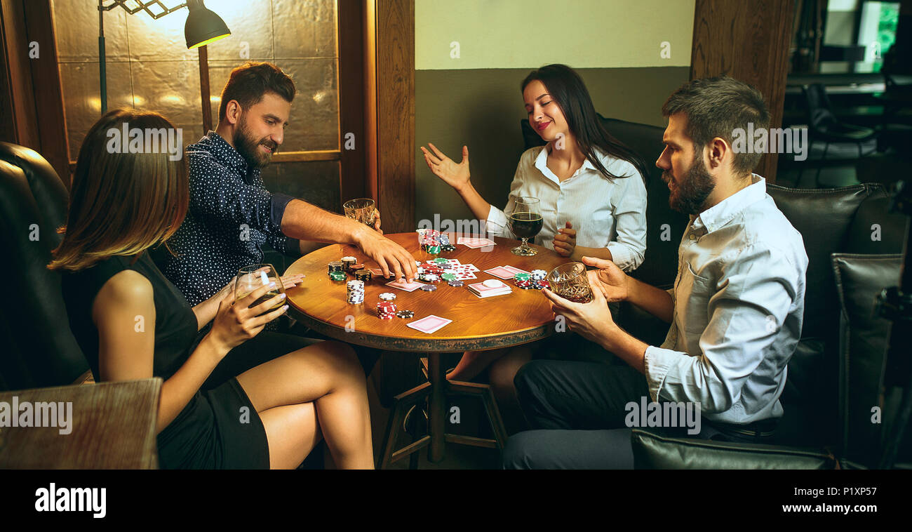 Side view photo of friends sitting at wooden table. Friends having fun ...