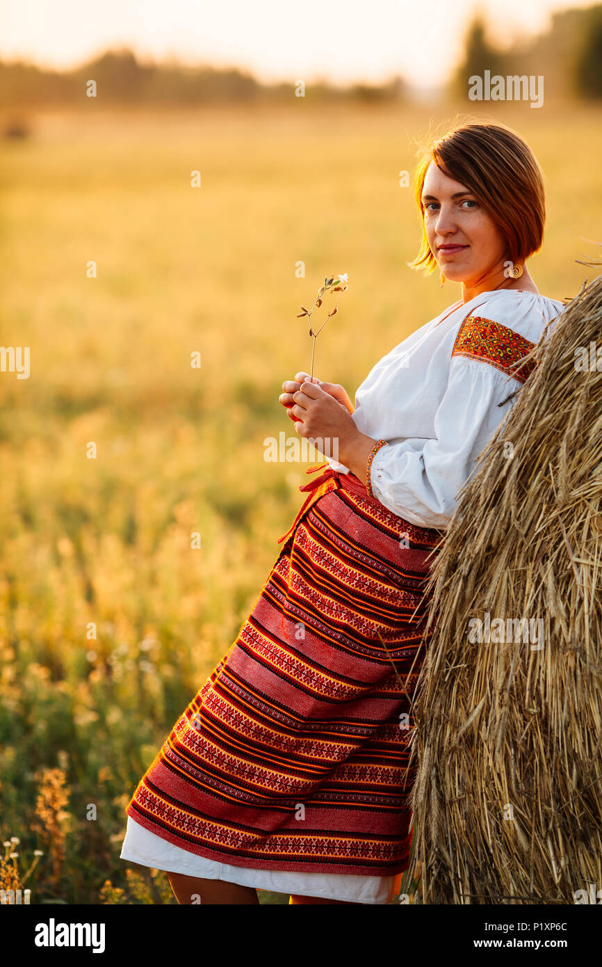 A girl in embroidered clothes in the field in the background of the ...