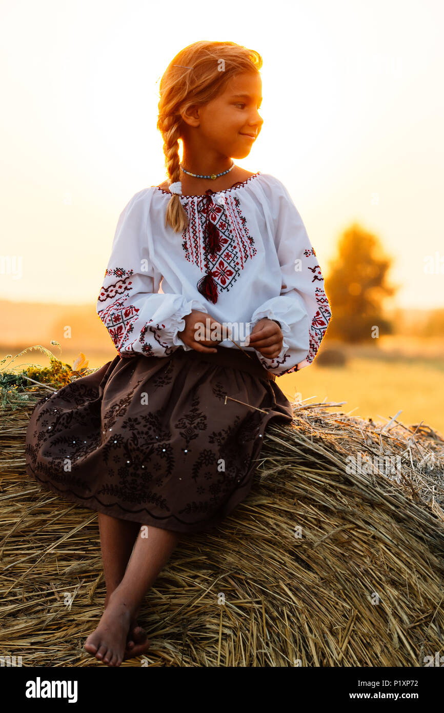 A girl in embroidered clothes in the field in the background of the ...