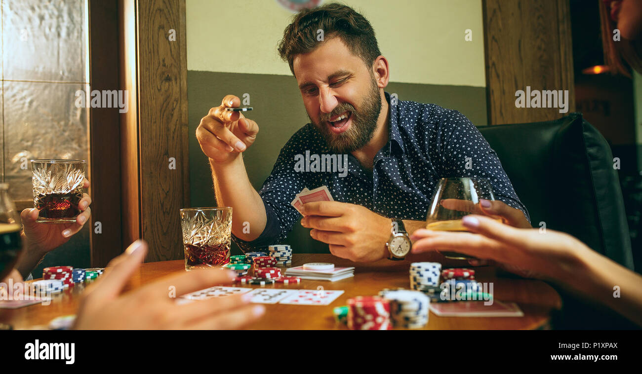 Side view photo of friends sitting at wooden table. Friends having fun ...