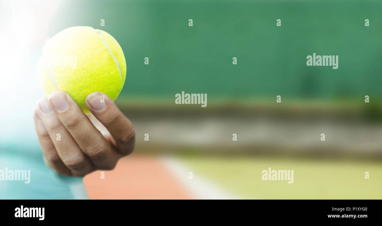 Hand holding tennis ball on court Stock Photo - Alamy