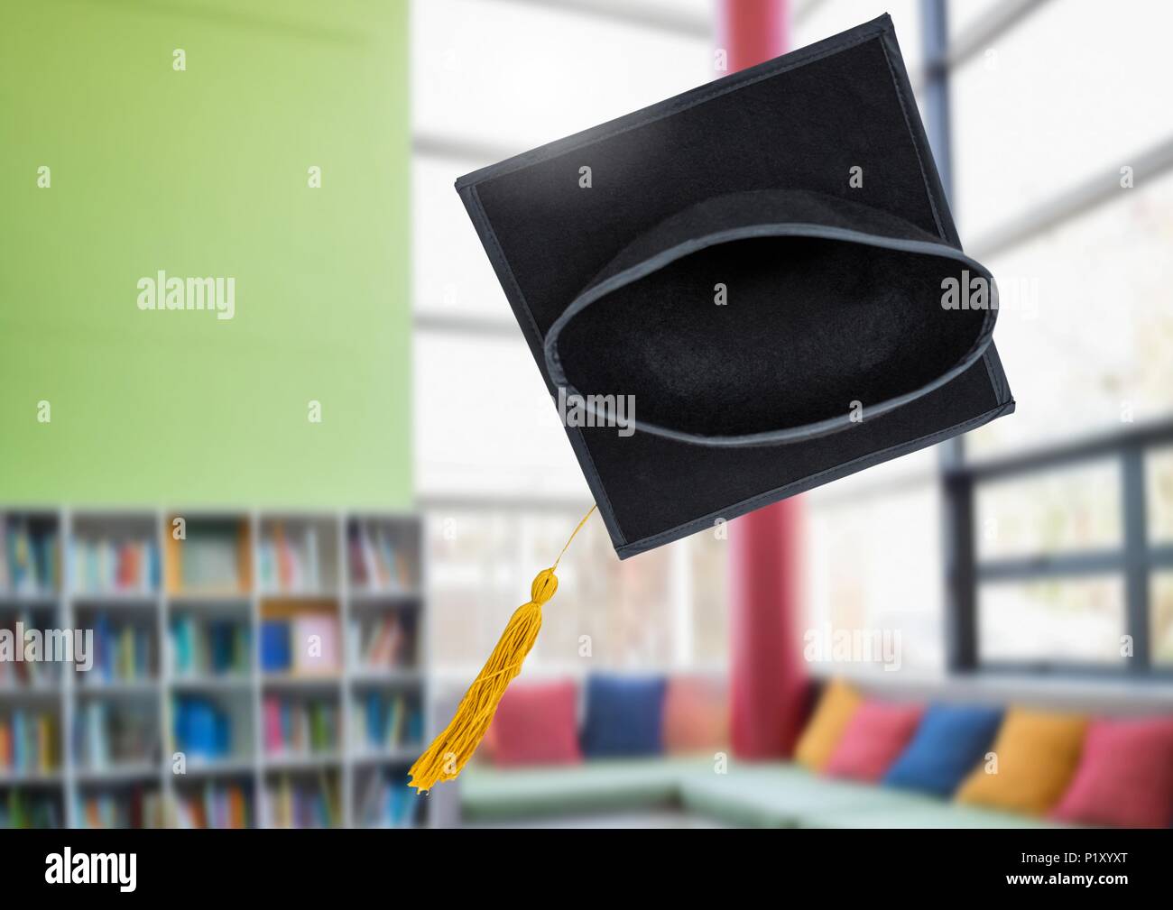Graduation hat in education library Stock Photo - Alamy