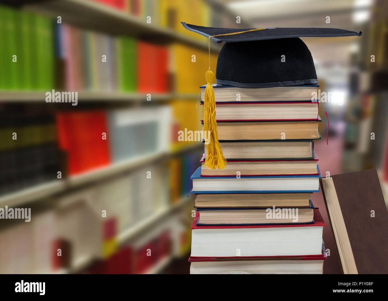 Books and graduation hat in education library Stock Photo - Alamy