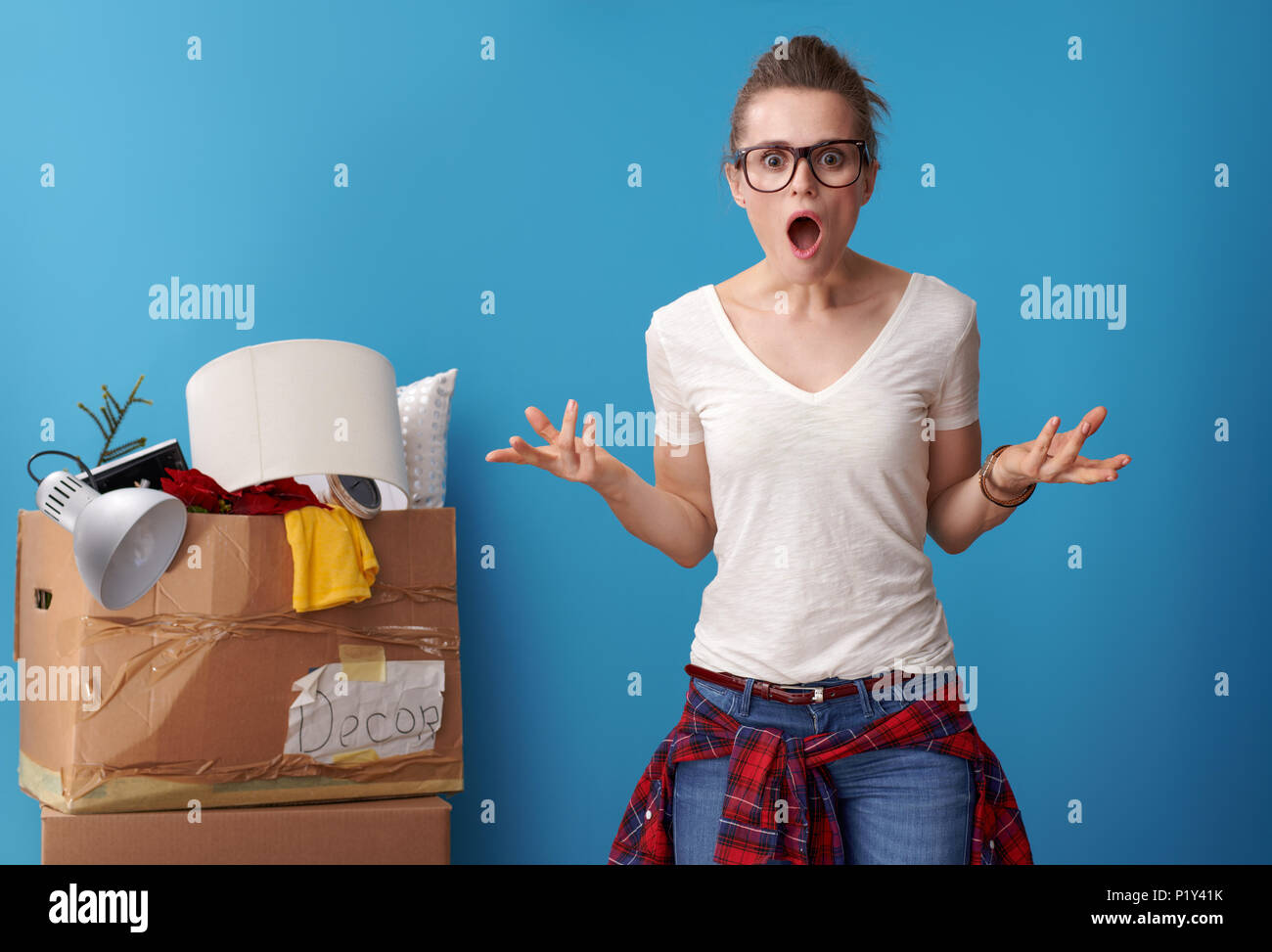 shocked modern woman in white shirt with an untidy cardboard box in the ...