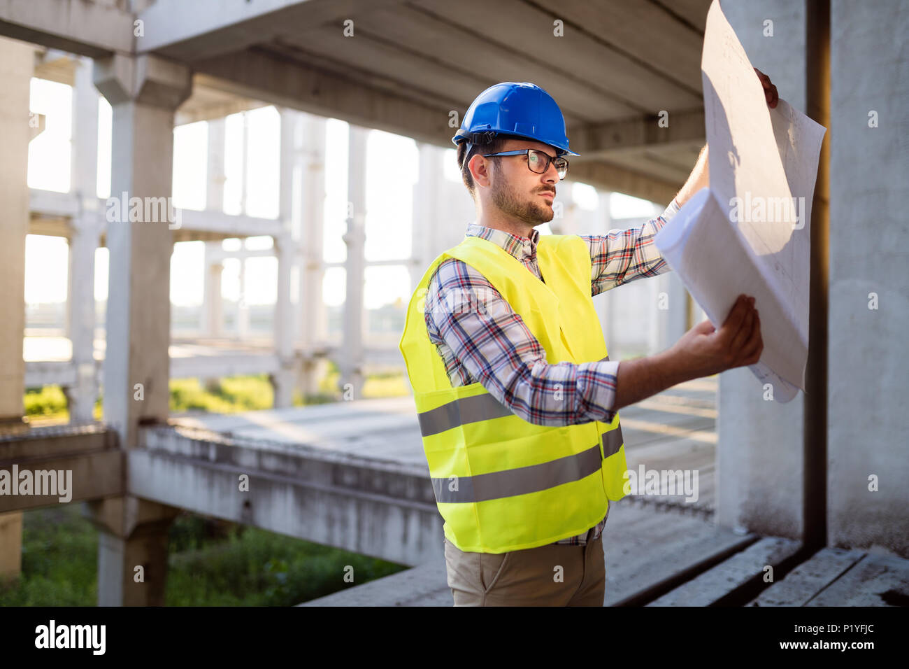 Architect holding rolled up blueprints at construction site Stock Photo ...