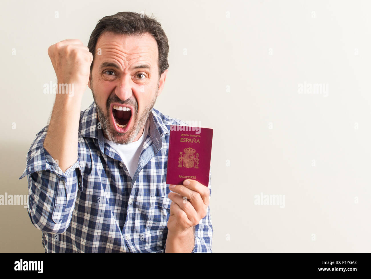 Senior man holding spanish passport annoyed and frustrated shouting ...