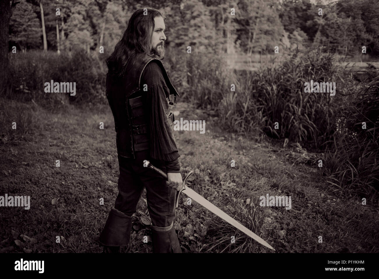 The bearded man knight. A guy in a medieval costume with a sword ...