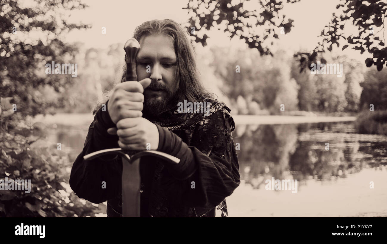 The bearded man knight. A guy in a medieval costume with a sword ...