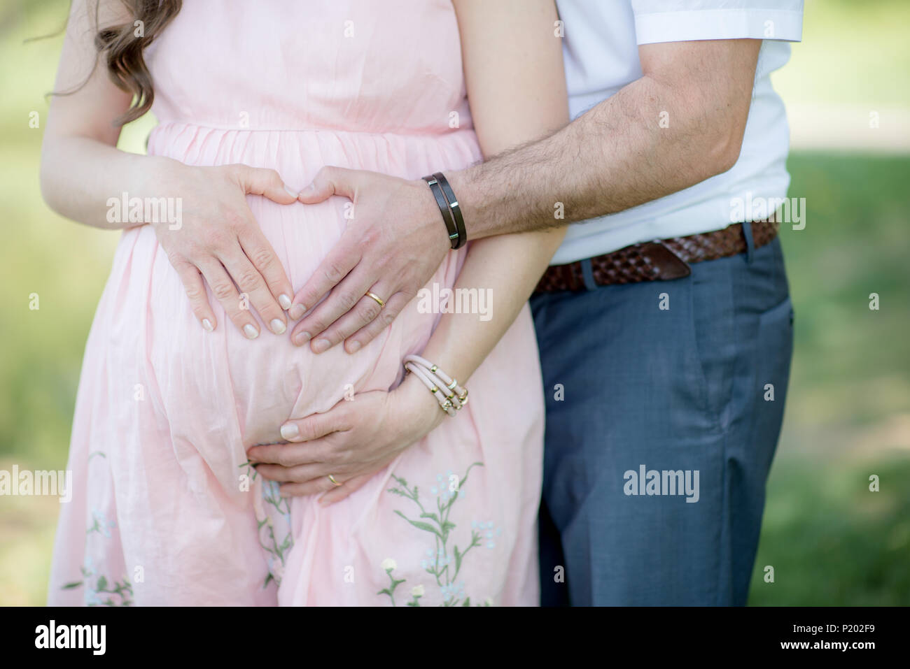 Happy and young pregnant couple hugging in nature - Detail of young ...