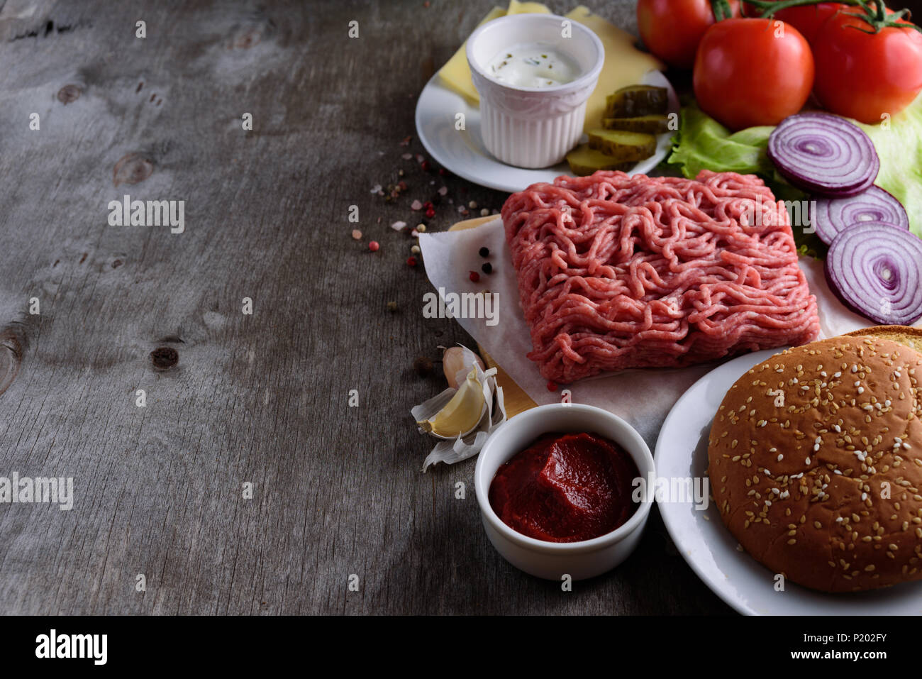 raw minced meat on paper, ingredients for burger with tomato, onion and ...