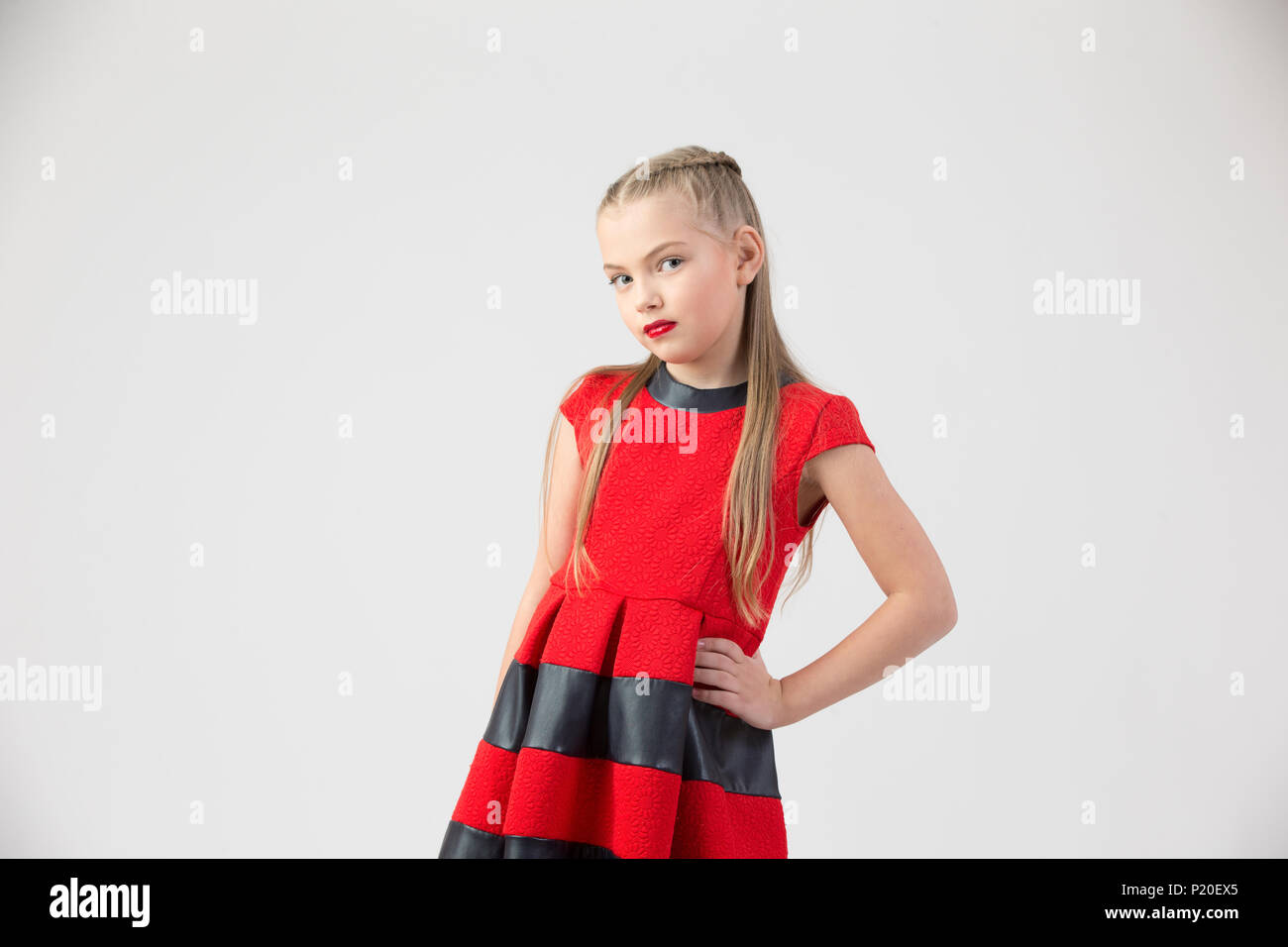 A teenaged blond girl in a red dress and brightly red lips on a white ... A teenaged blond girl in a red dress and brightly red lips on a white ...