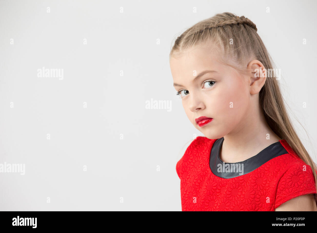 A teenaged blond girl in a red dress and brightly red lips on a white ... A teenaged blond girl in a red dress and brightly red lips on a white ...