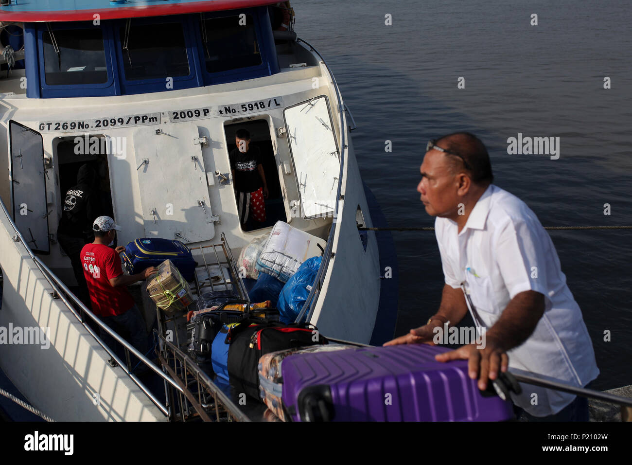 Ferry workers loading up passengers belonging and luggage in Port Klang ...