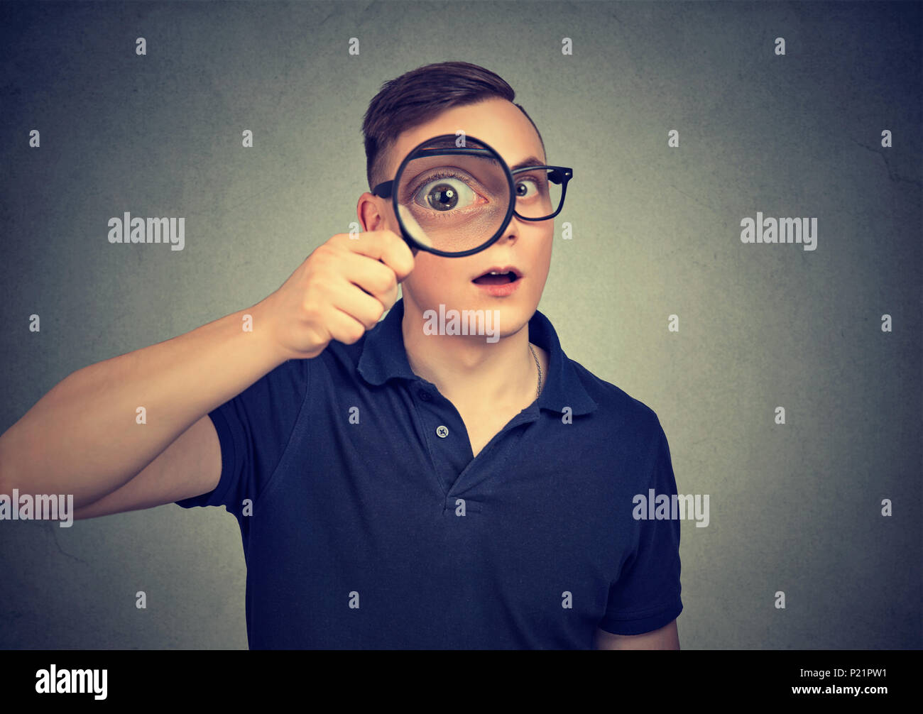 Curious man looking through a magnifying glass Stock Photo - Alamy