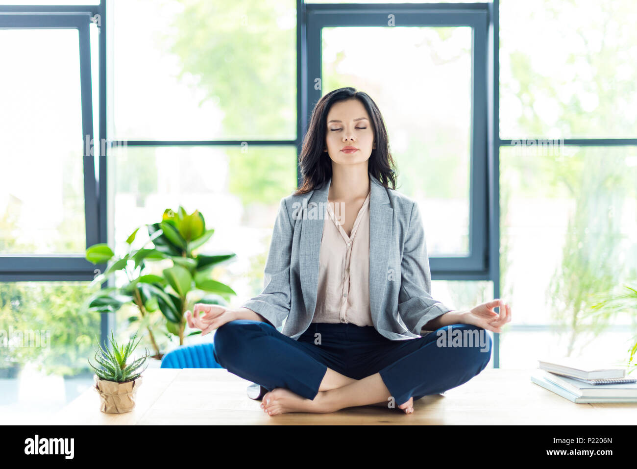 relaxed businesswoman with eyes closed meditating at workplace in ...