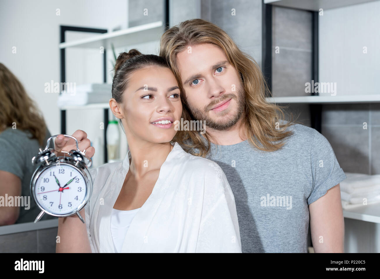 young couple hugging while woman holding alarm clock in bathroom Stock ...