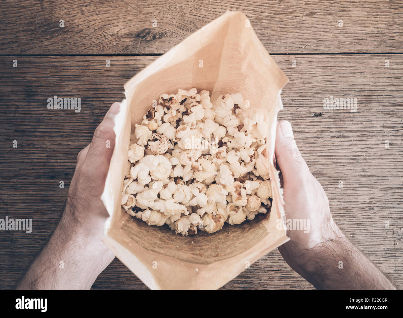directly above shot of hands holding brown paper bag filled with ...