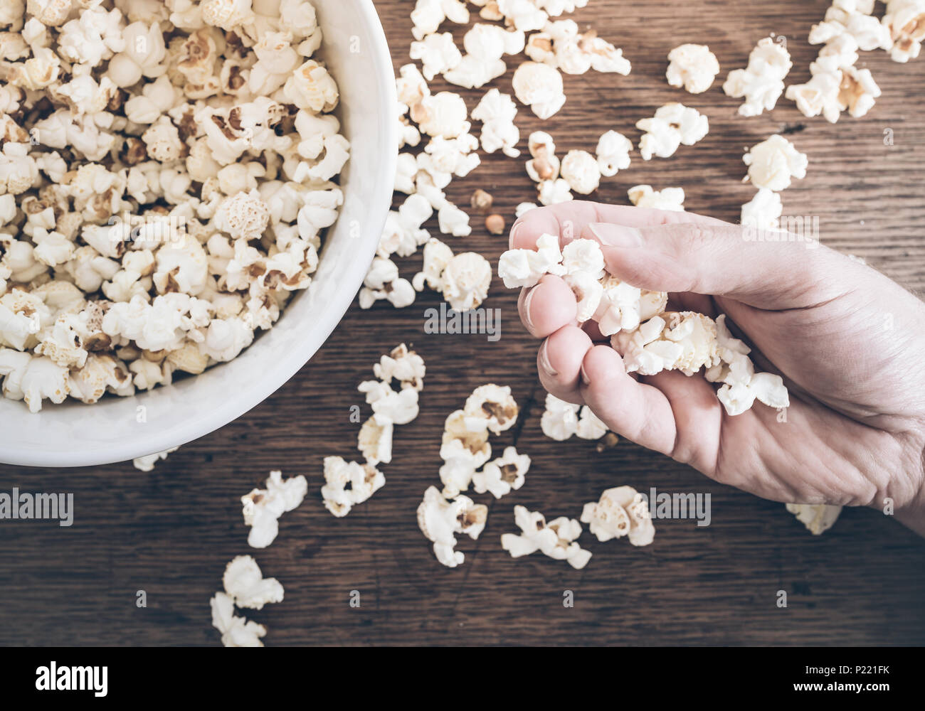 close-up of hand holding popcorn above wooden table Stock Photo - Alamy