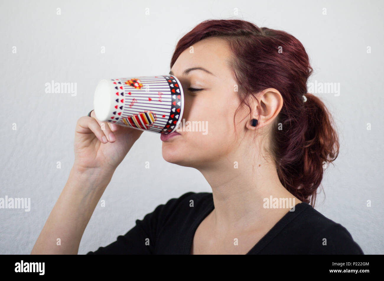 Young girl drinks tea, drinks coffee, cups, white background, studio ...