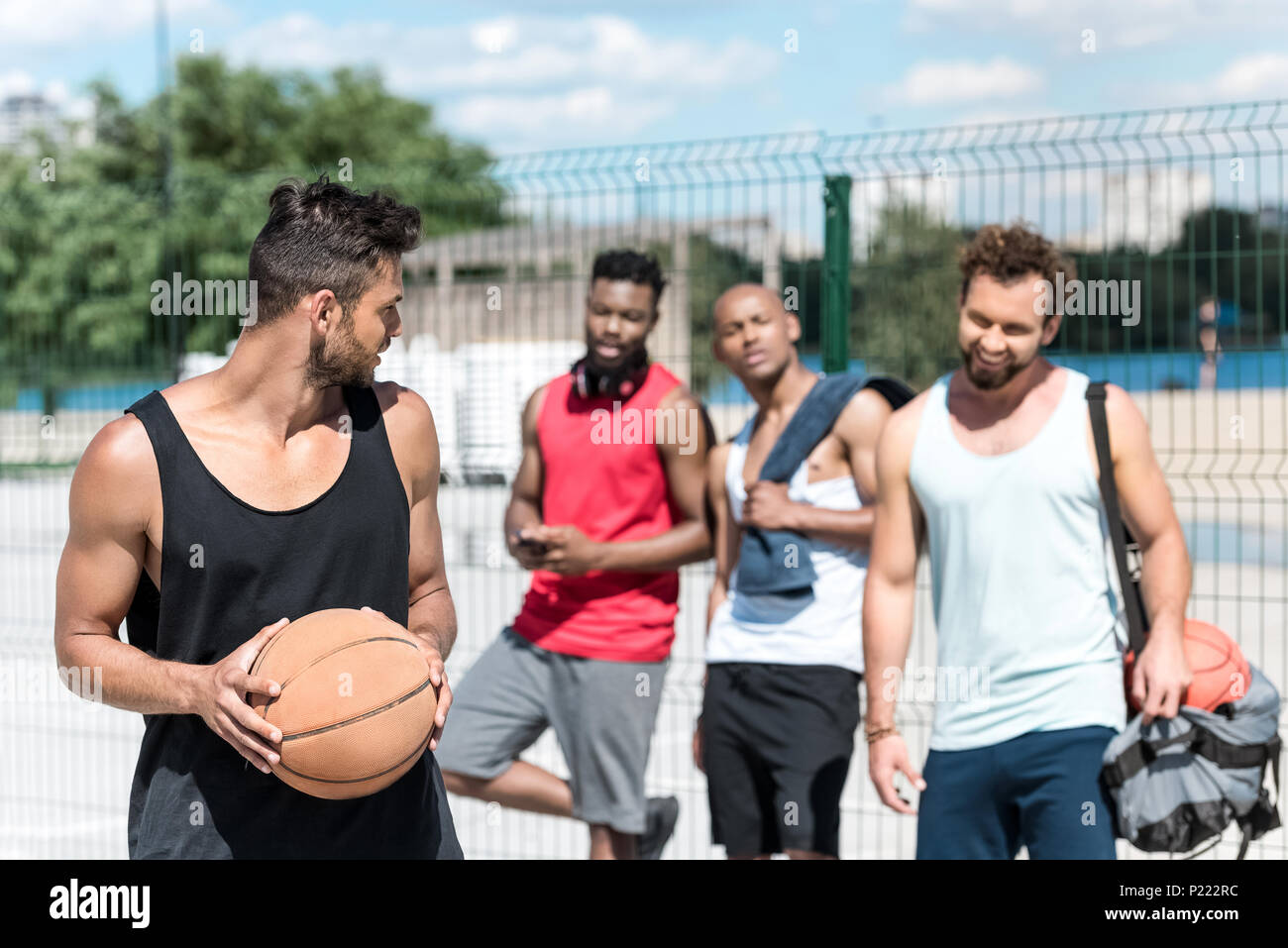 multicultural basketball team playing basketball on court in summer ...