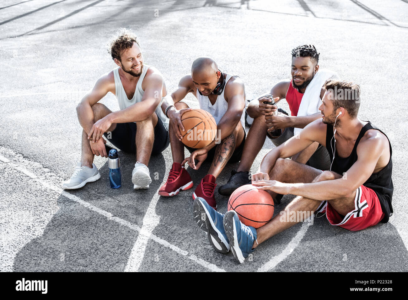 multiethnic group of basketball players resting on court together Stock ...