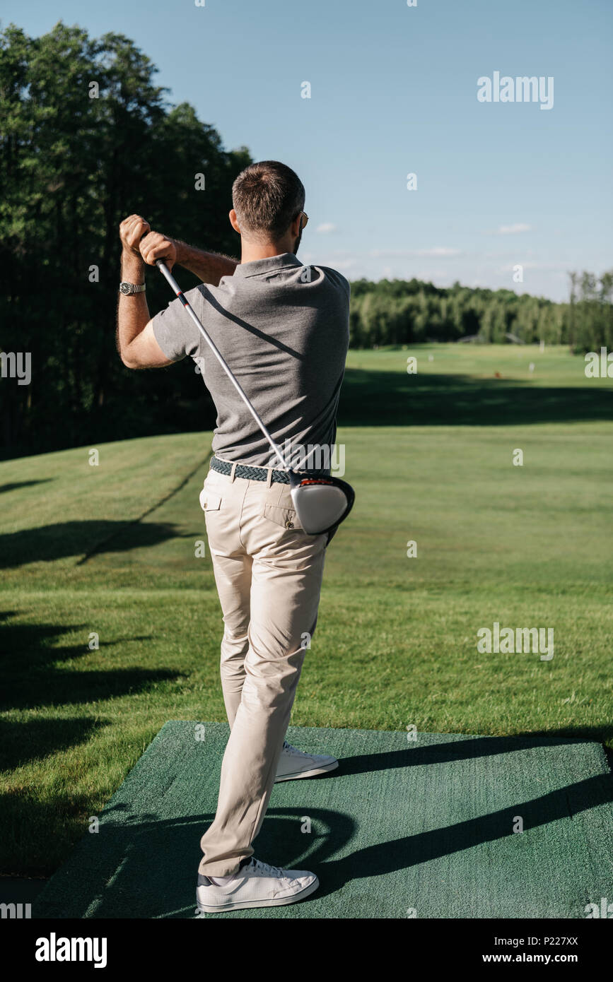Back view of man holding golf club while playing golf outdoors Stock ...