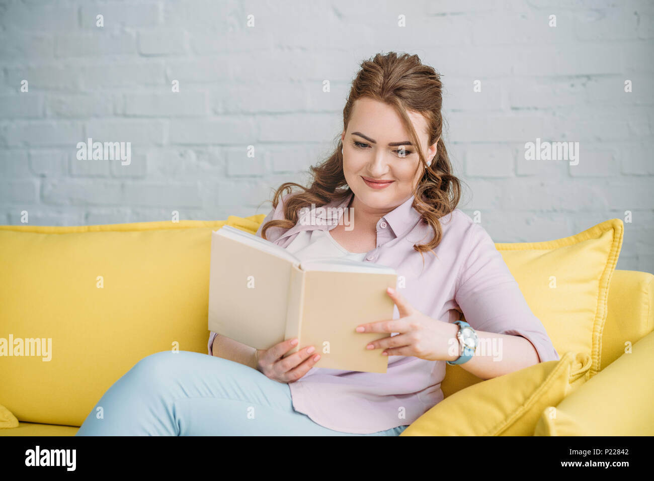 beautiful woman reading book on sofa at home Stock Photo - Alamy