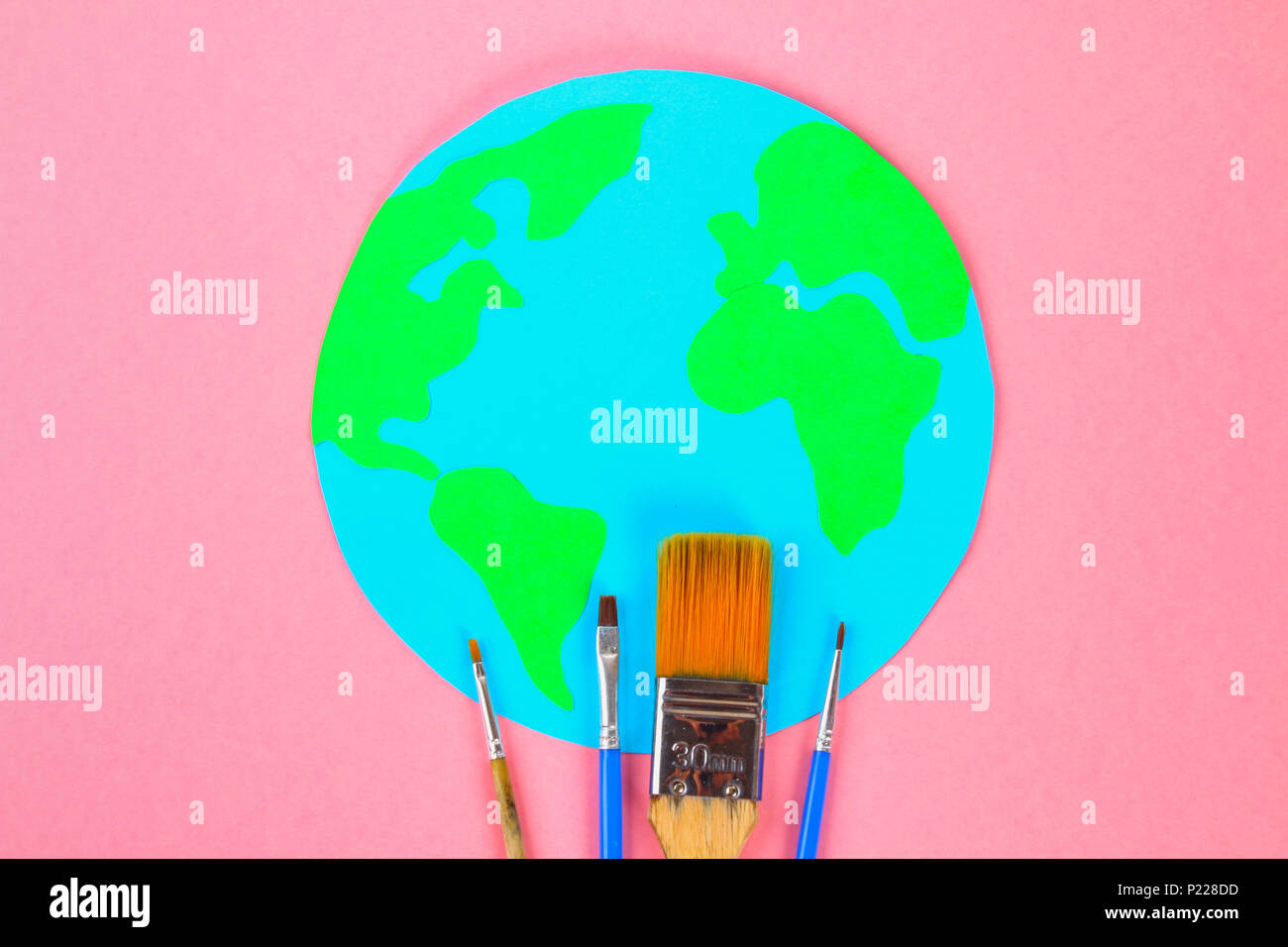 World art. Planet Earth and pencils, brushes on a pastel pink ...