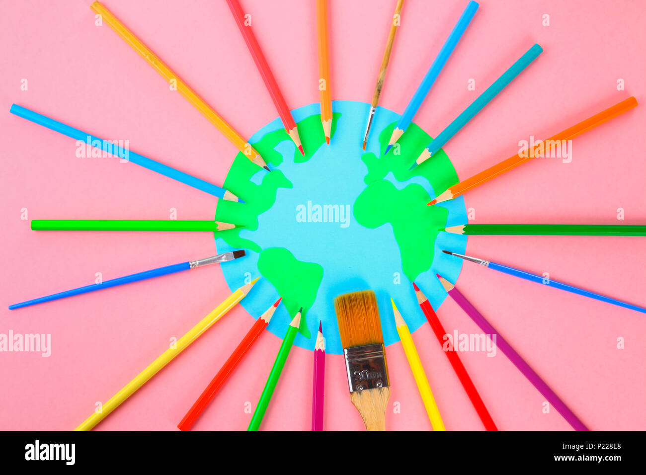 World art. Planet Earth and pencils, brushes on a pastel pink ...