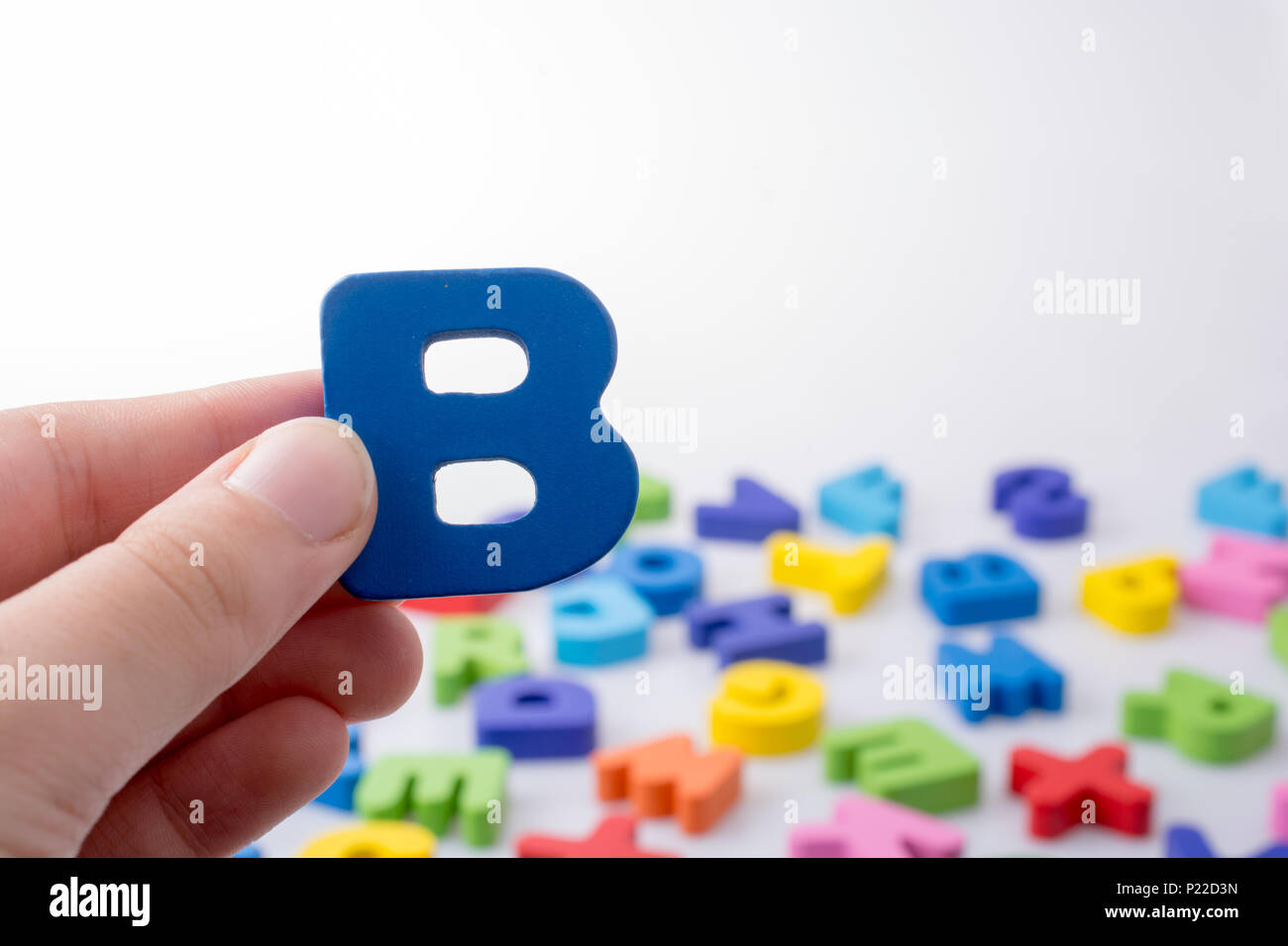 Letter B in hand beside colorful alphabet letter blocks scattered ...