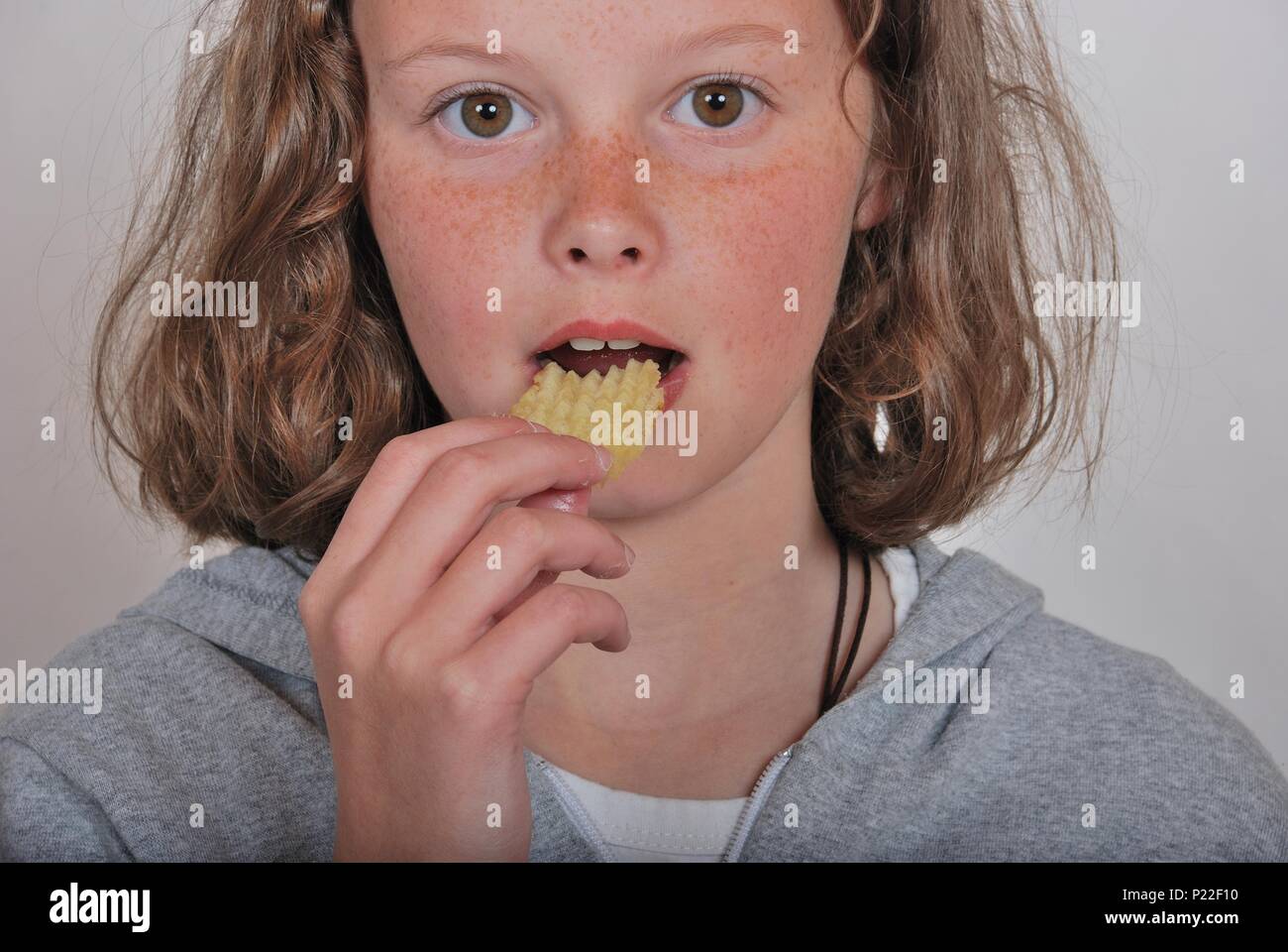 Girl eating chip Stock Photo - Alamy