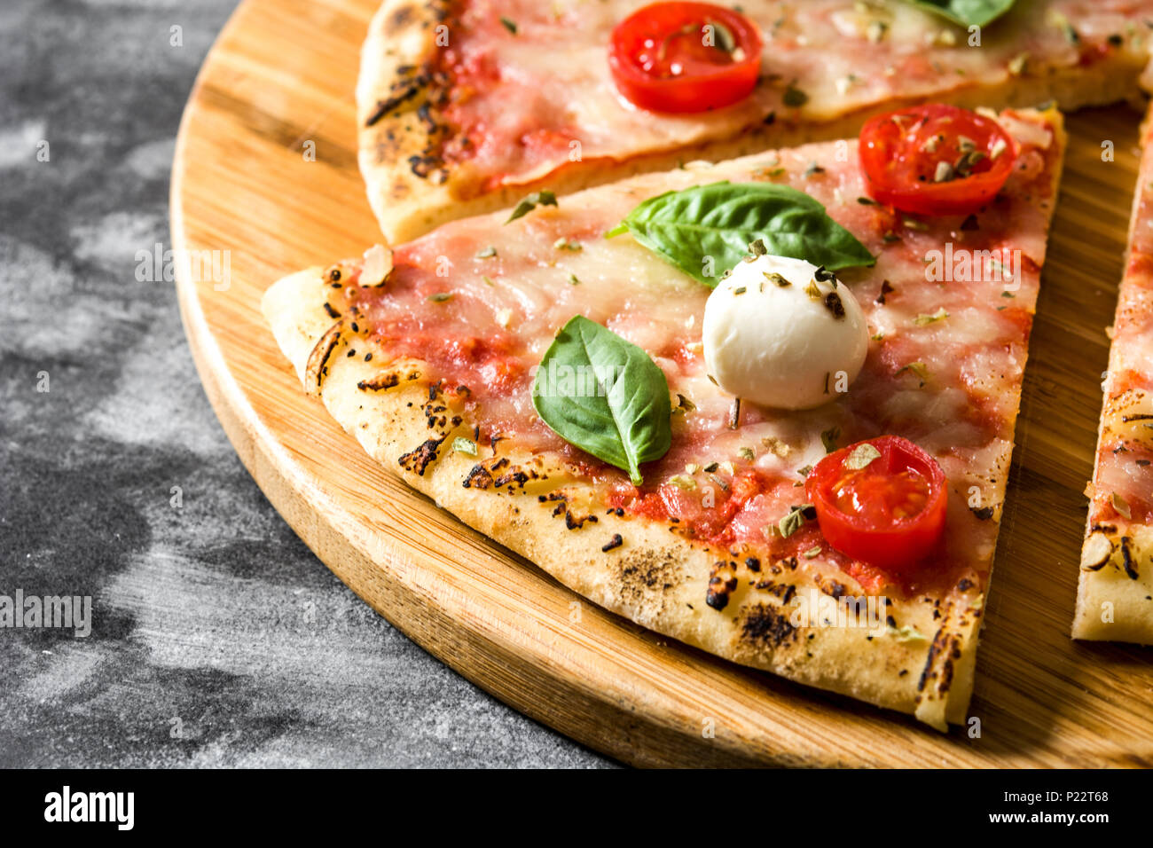 Italian pizza slice with tomatoes, cheese and basil on black stone ...