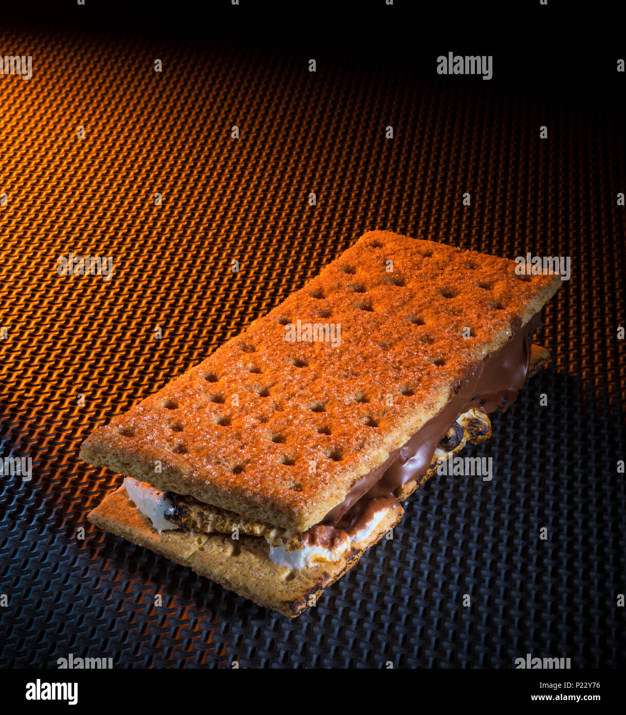 Smore ready to eat on a dark background with orange coming from behind ...