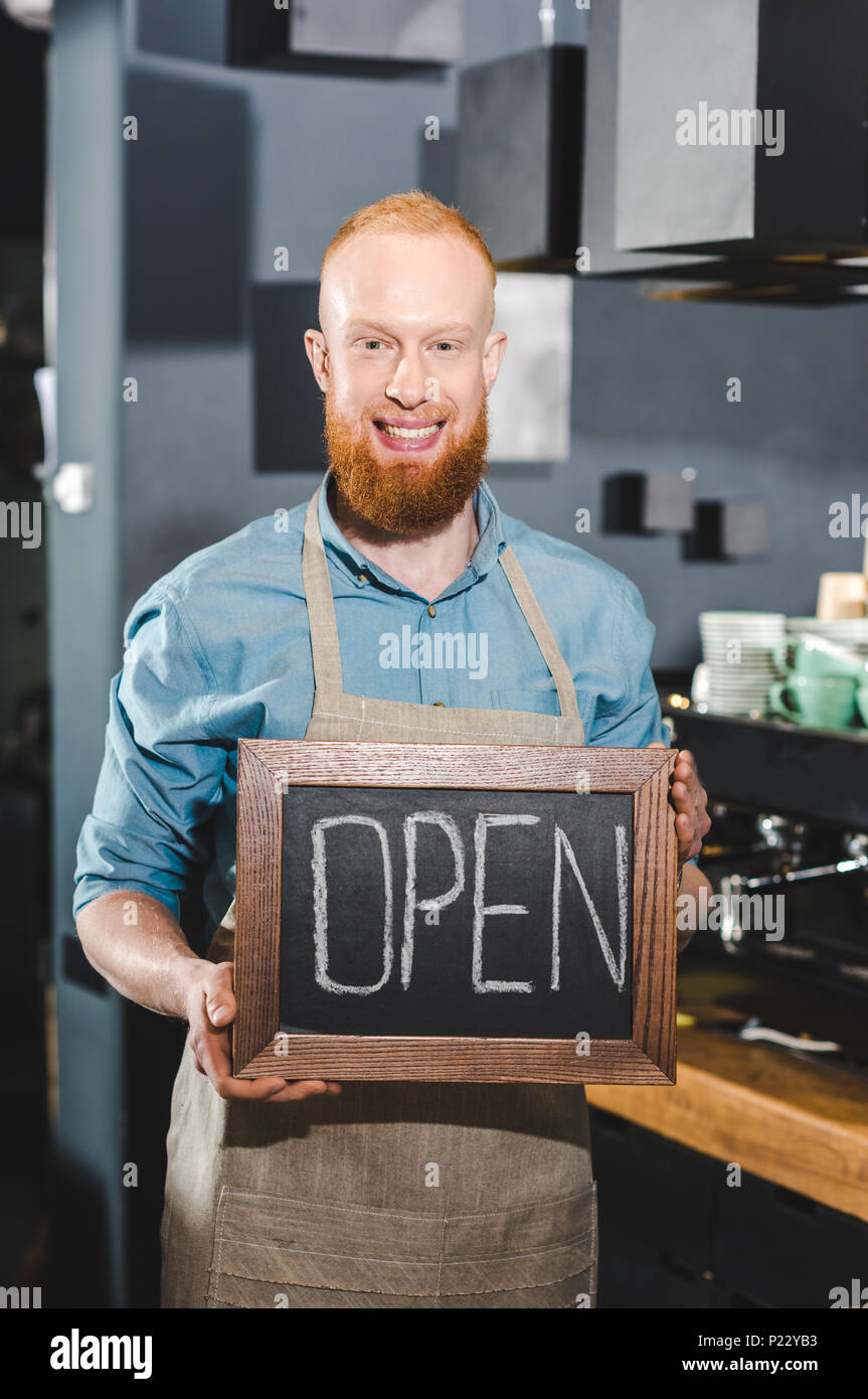 smiling young male barista holding chalkboard with lettering open in ...
