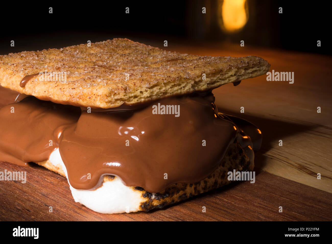 Lit camping lantern behind a big thick smore on a wood table Stock ...