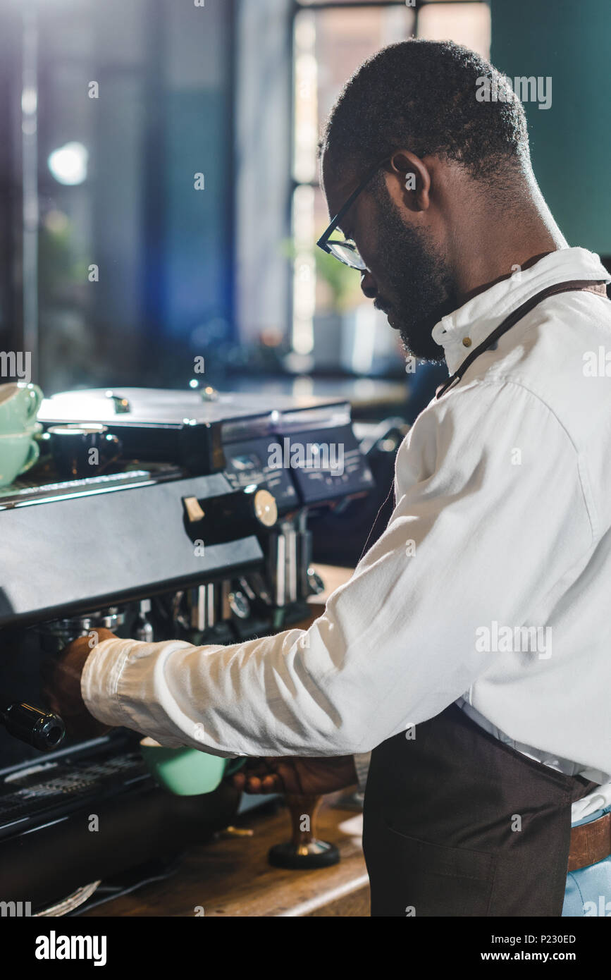 side view of young african american barista in eyeglasses working with ...