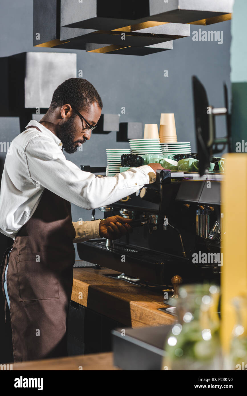 side view of african american barista in eyeglasses working with coffee ...