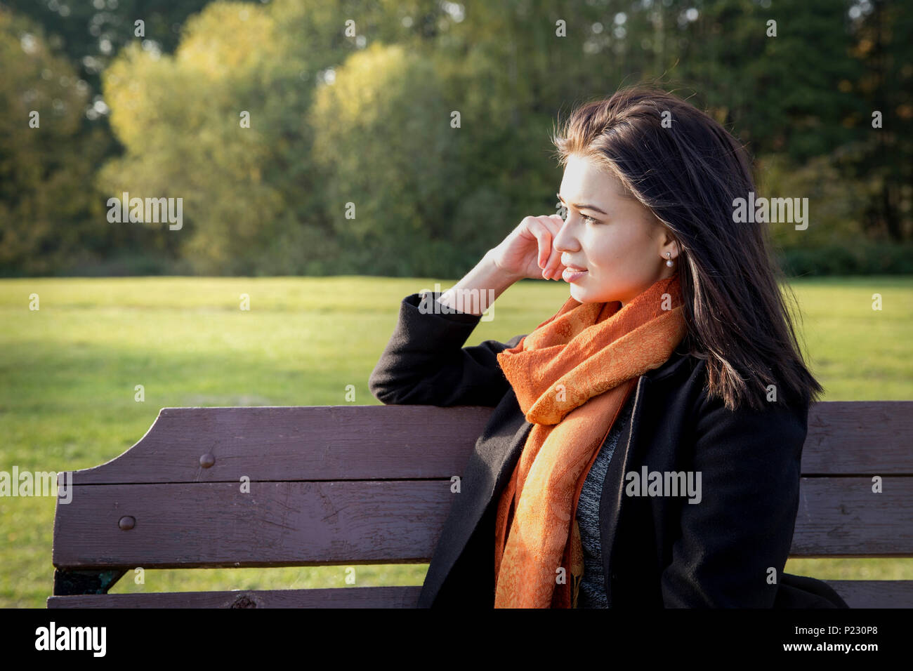 Young attractive woman seating on a bench in park Stock Photo - Alamy