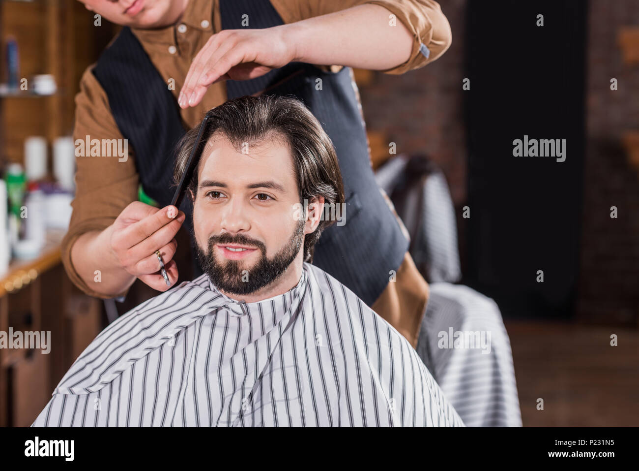 cropped shot of handsome young man getting haircut from professional ...