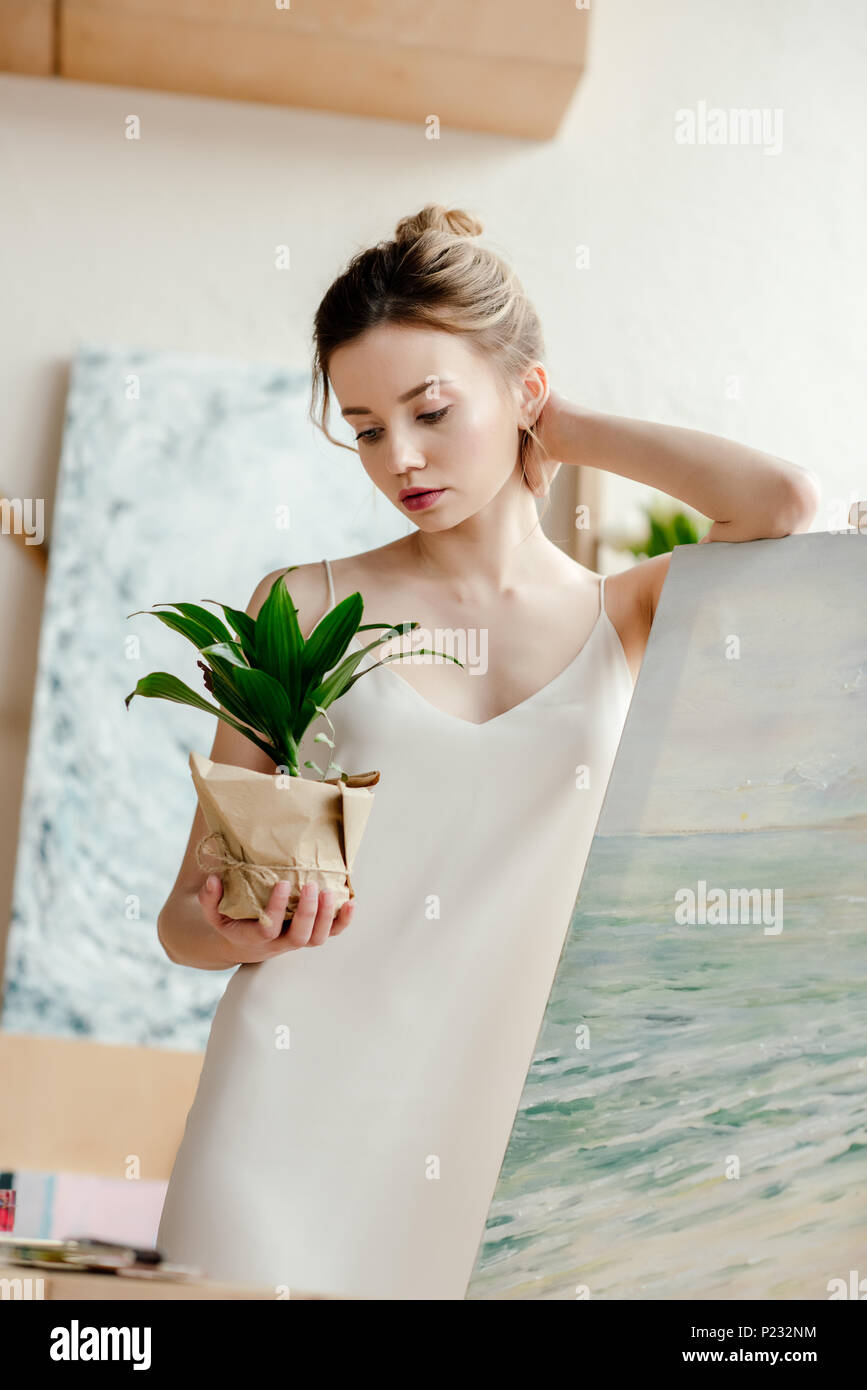 beautiful young artist leaning at picture on easel and looking at green ...