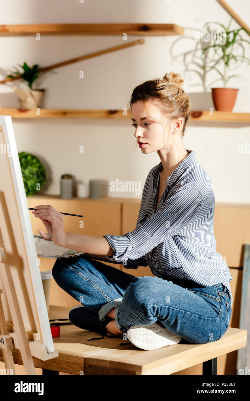 female artist sitting on table and drawing picture by paintbrush Stock ...