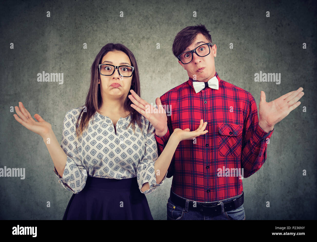 Young stylish couple in glasses looking clueless and shrugging with ...