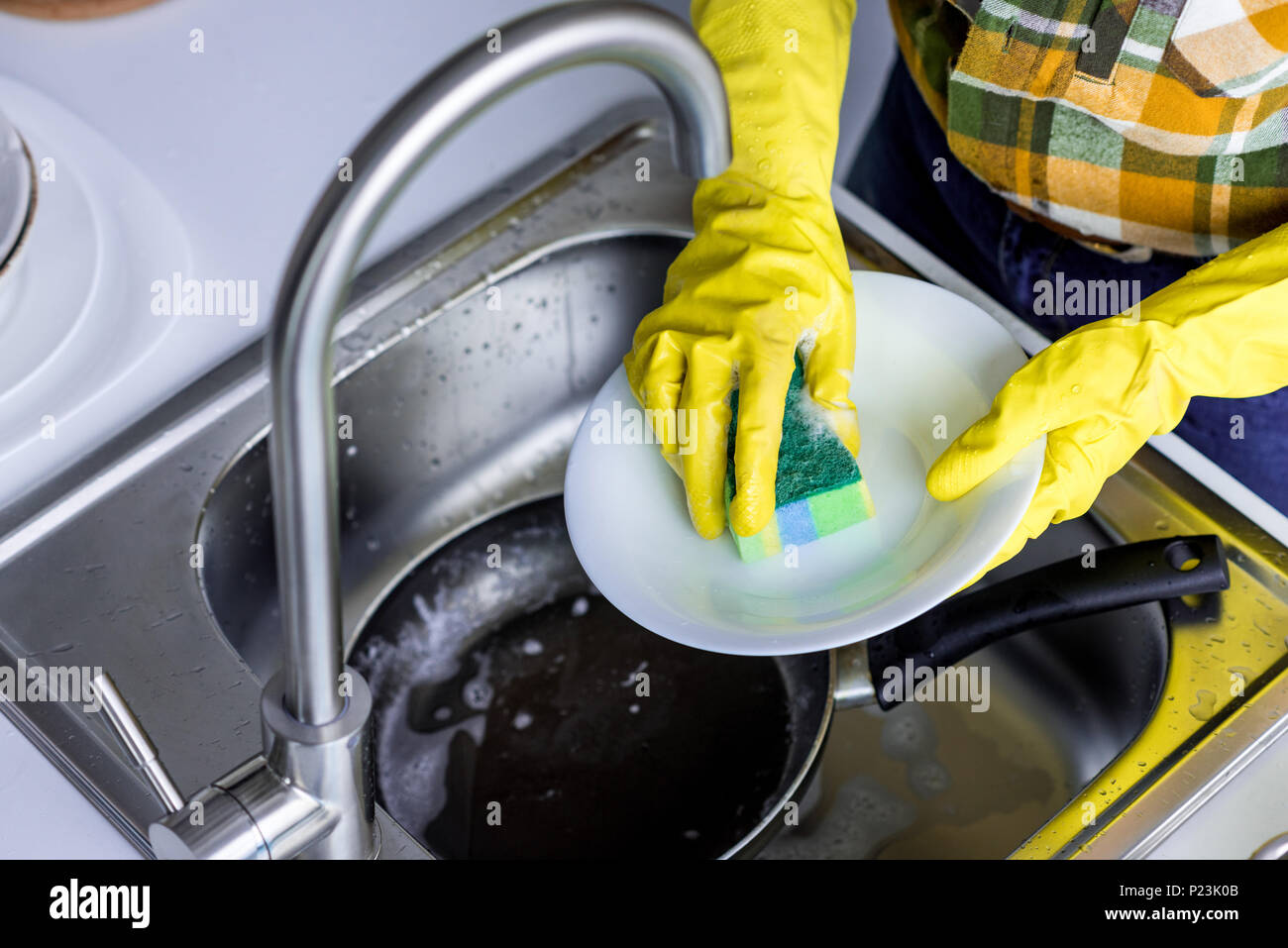 cropped image of woman washing plate with washing sponge in kitchen ...