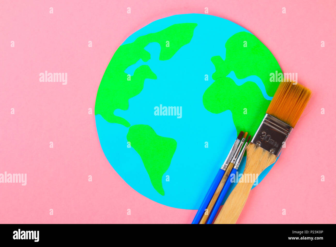 World art. Planet Earth and pencils, brushes on a pastel pink ...