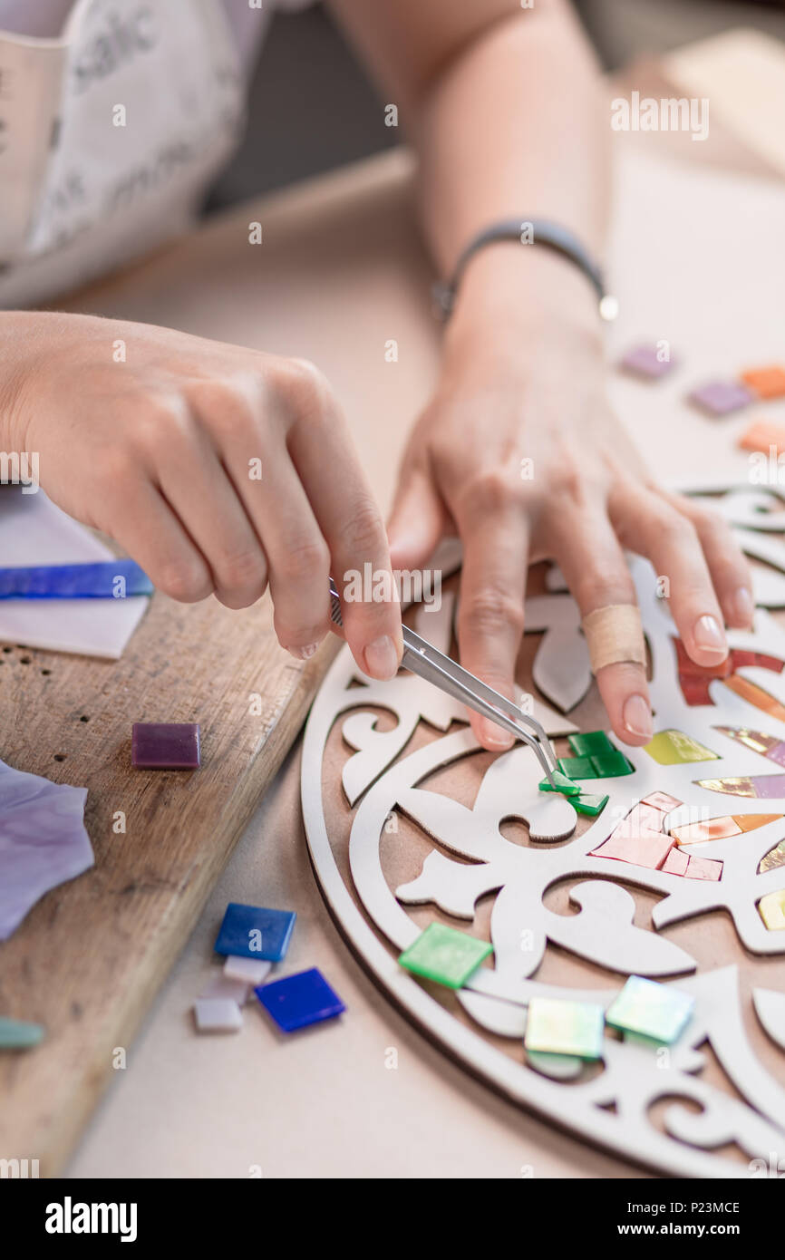 Workplace of the mosaic master: women's hands holding tool for mosaic ...