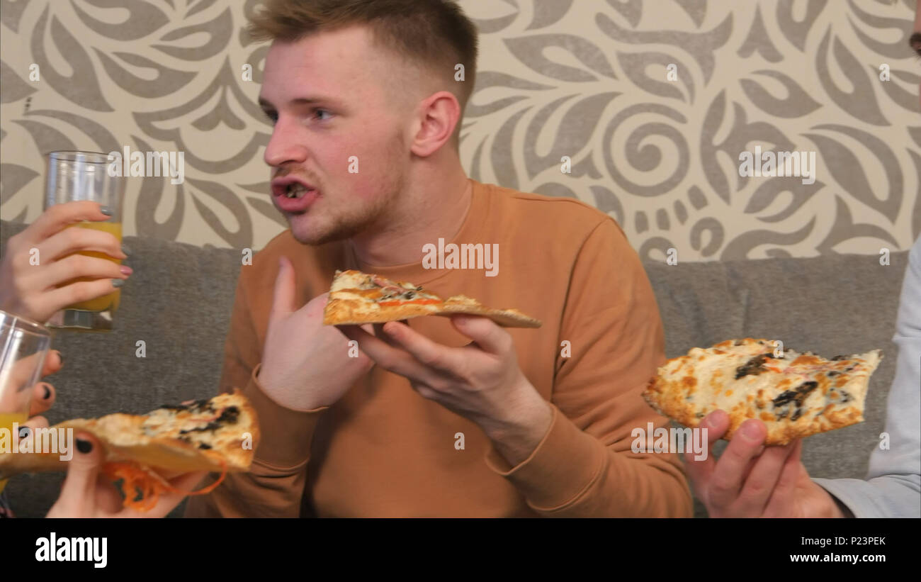 The cheerful company of youth eating a pizza and talking Stock Photo ...